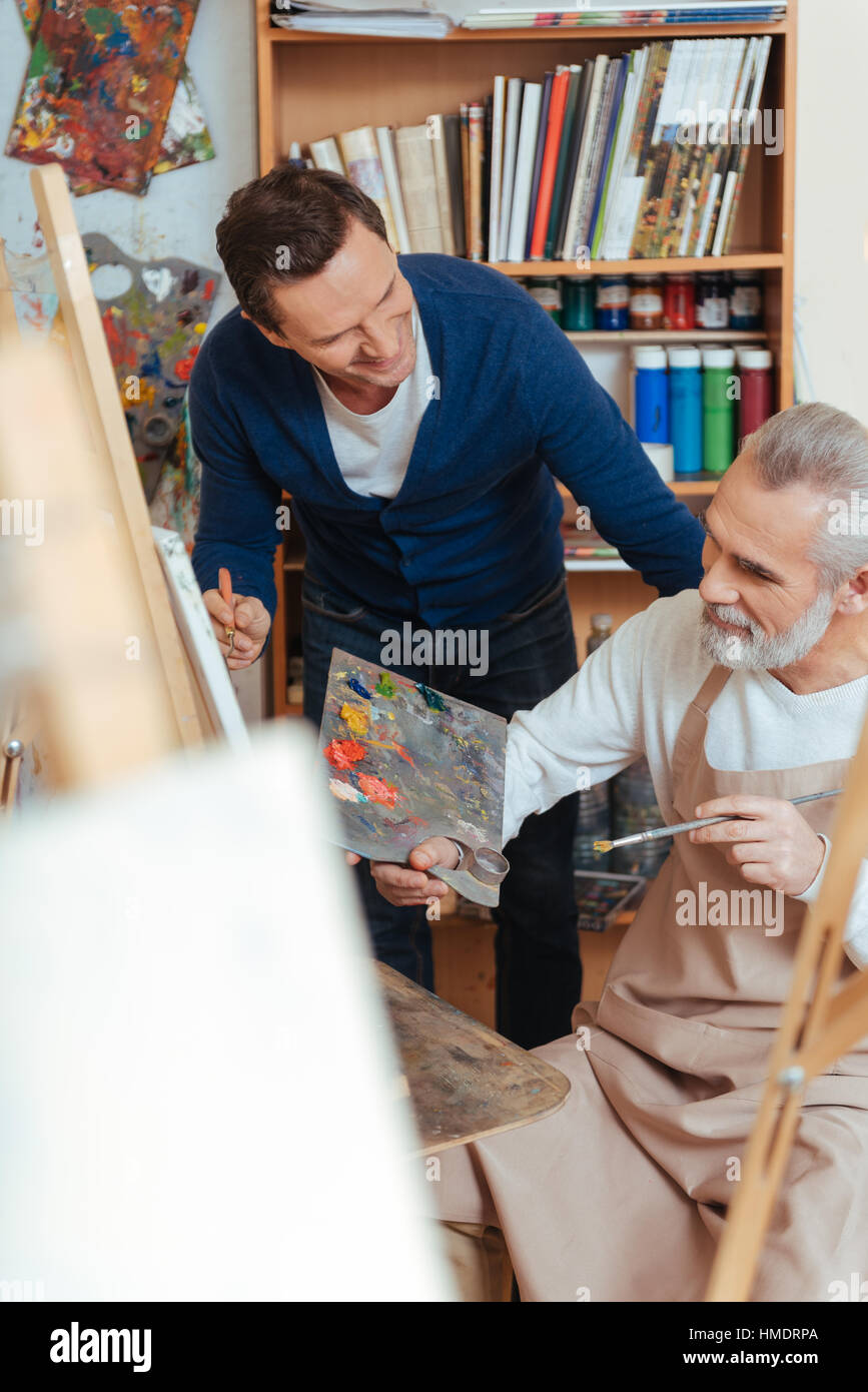 Smiling artist helping elderly man in painting Stock Photo - Alamy