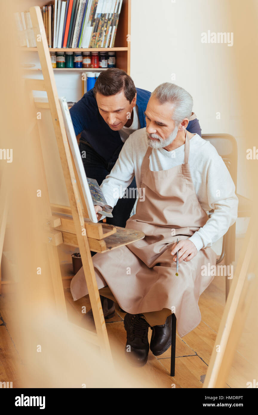 Talented artist helping elderly man in painting Stock Photo - Alamy