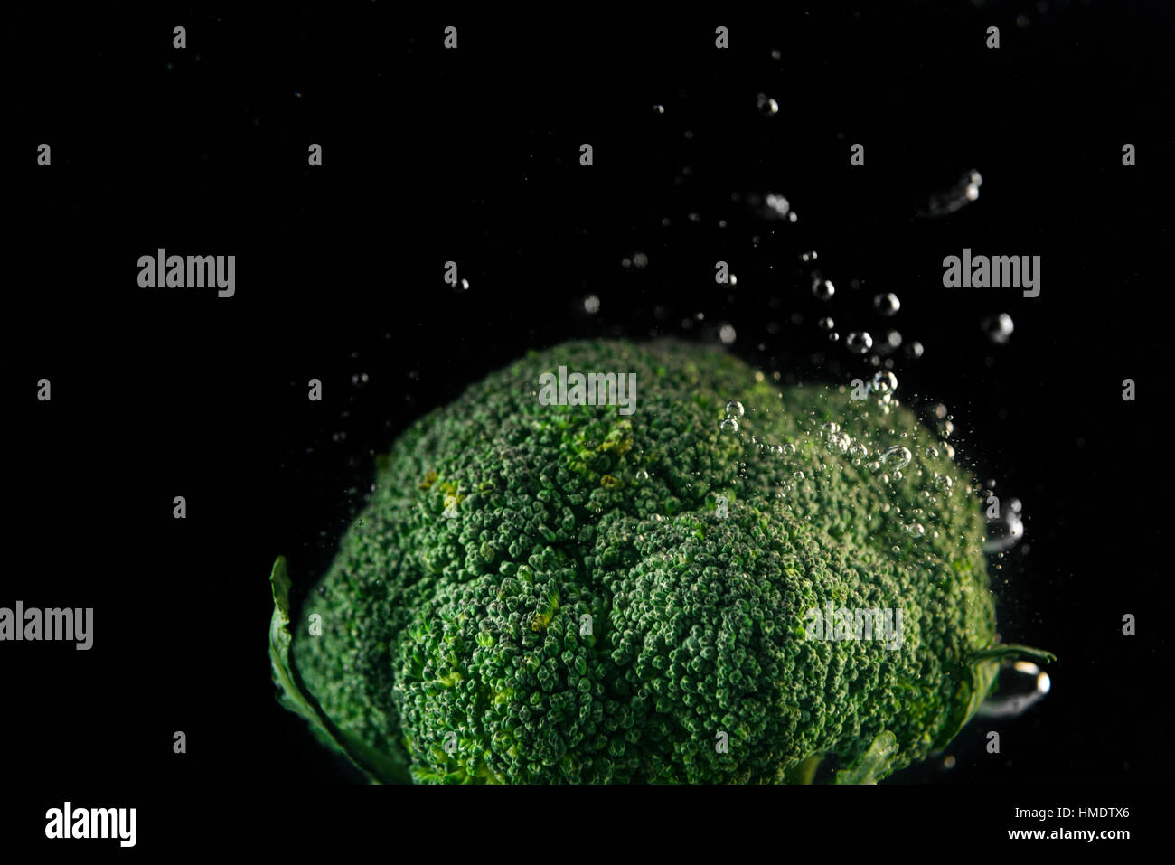 Fresh green broccoli dropped into water isolated on black background ...