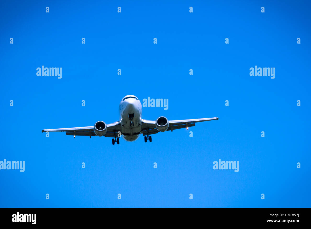 Jet airplane flying overhead close-up on a blue sky background Stock ...