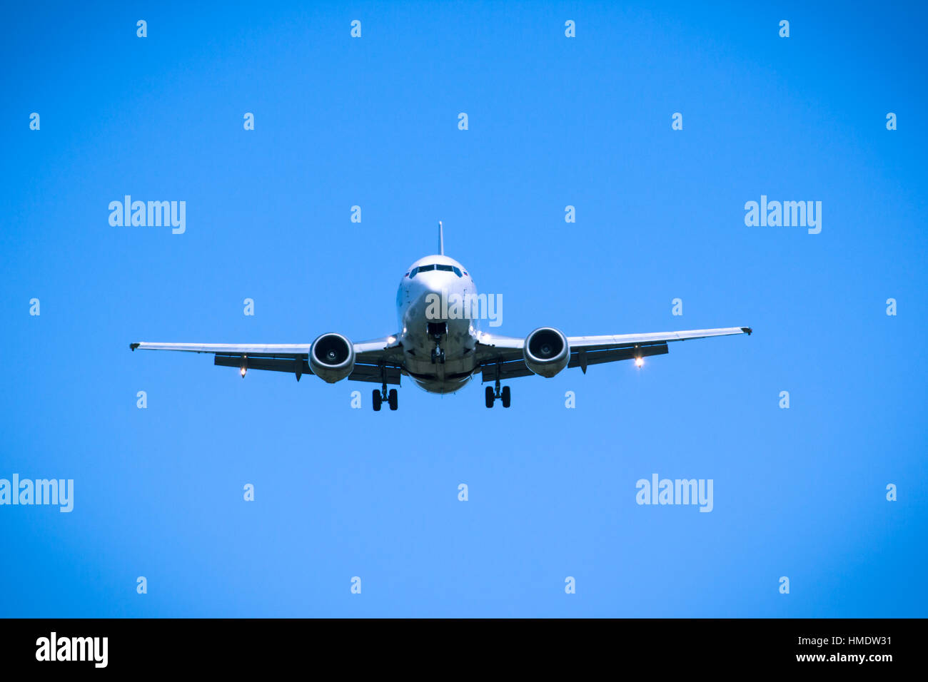 Jet airplane flying overhead close-up on a blue sky background Stock ...