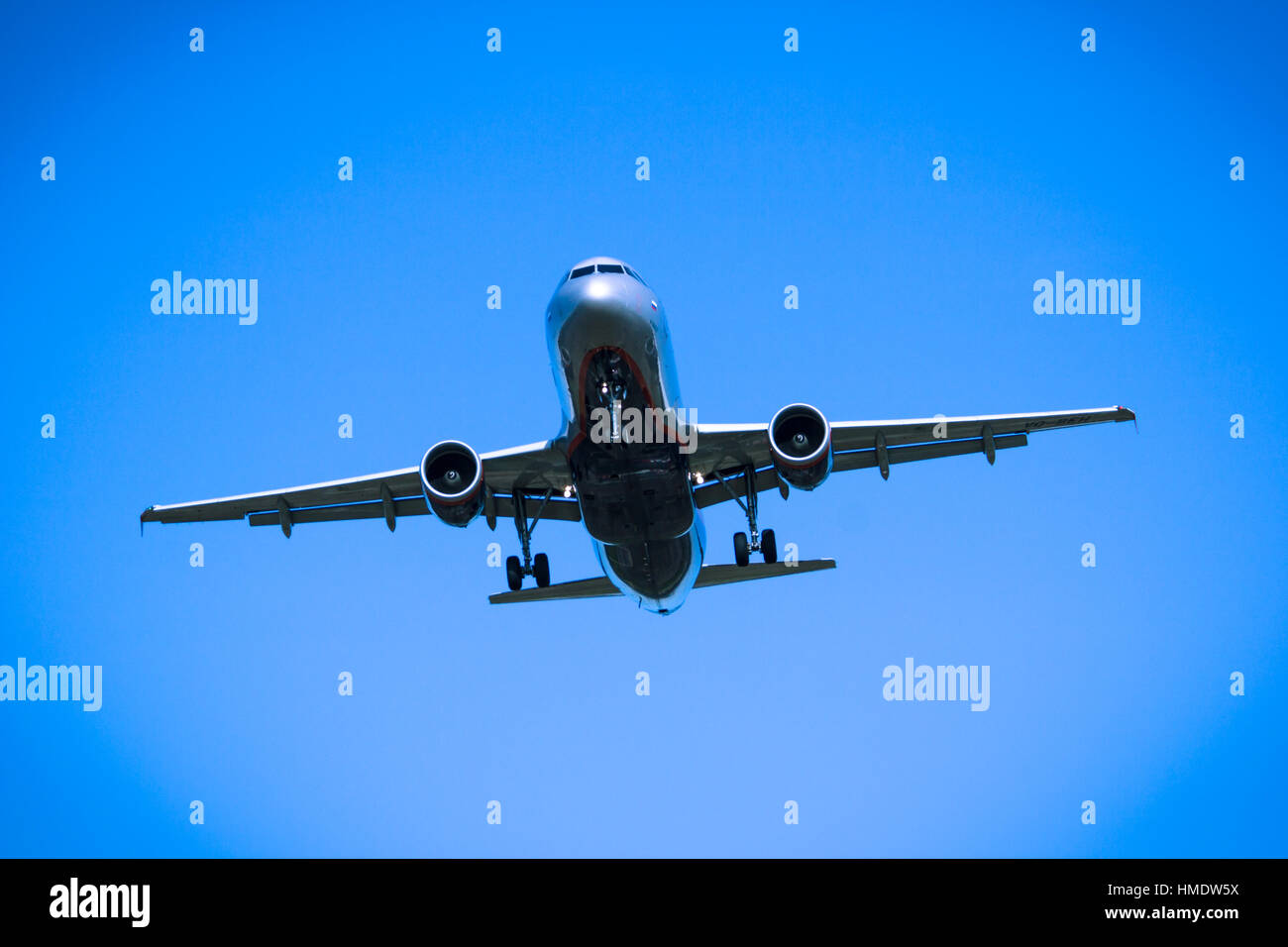 Jet airplane flying overhead close-up on a blue sky background Stock ...