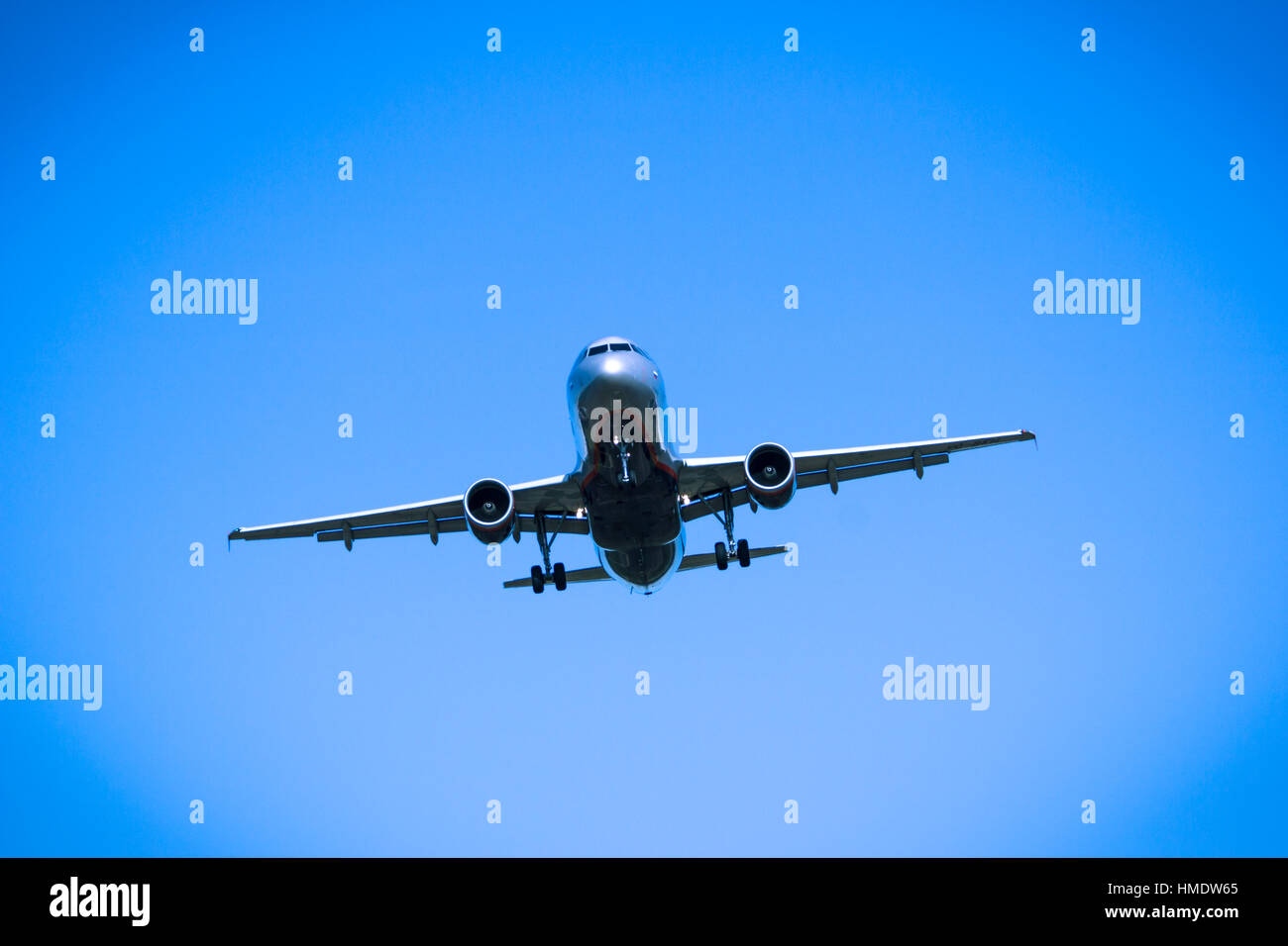 Jet airplane flying overhead close-up on a blue sky background Stock ...