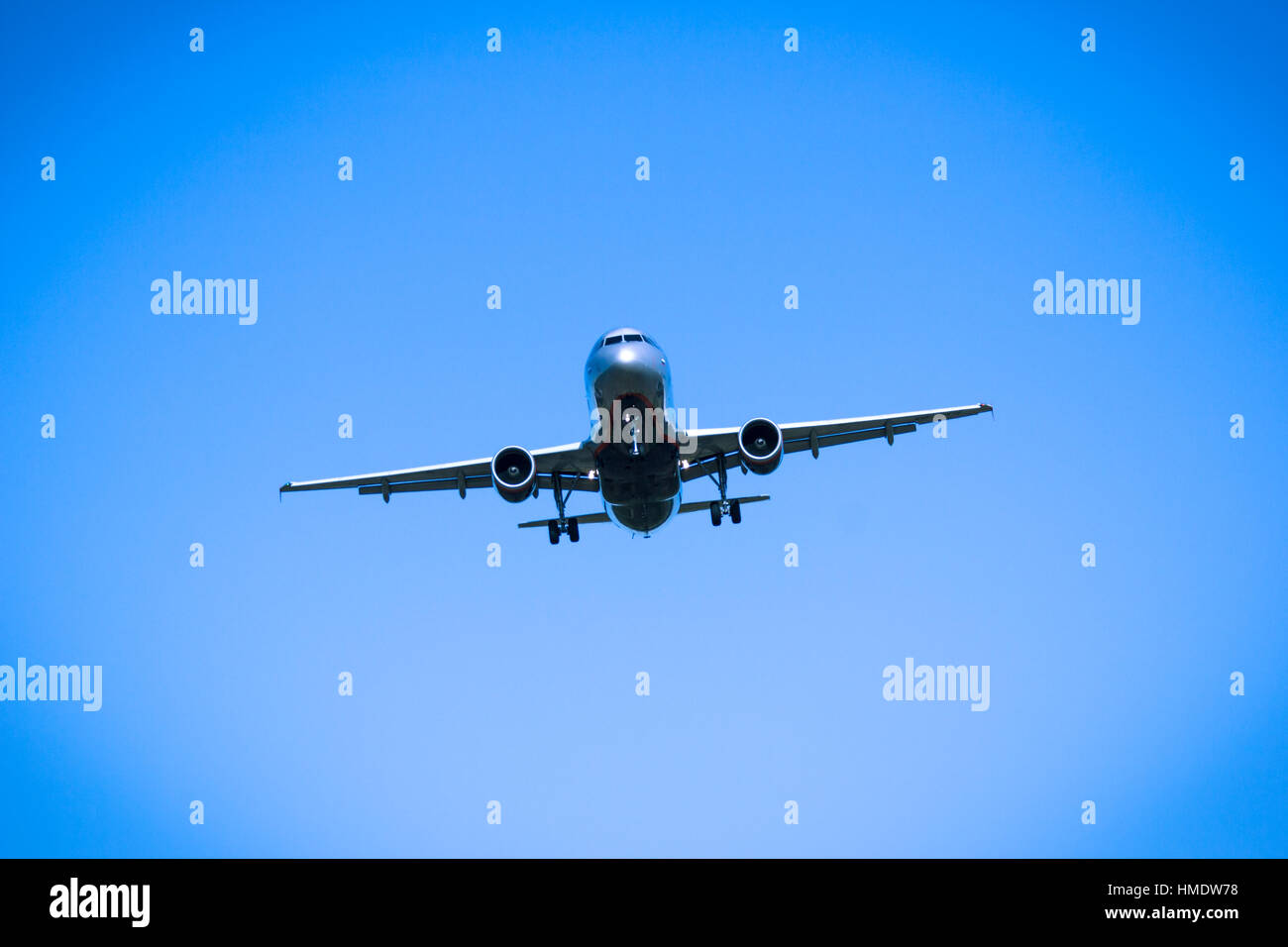 Jet airplane flying overhead close-up on a blue sky background Stock ...