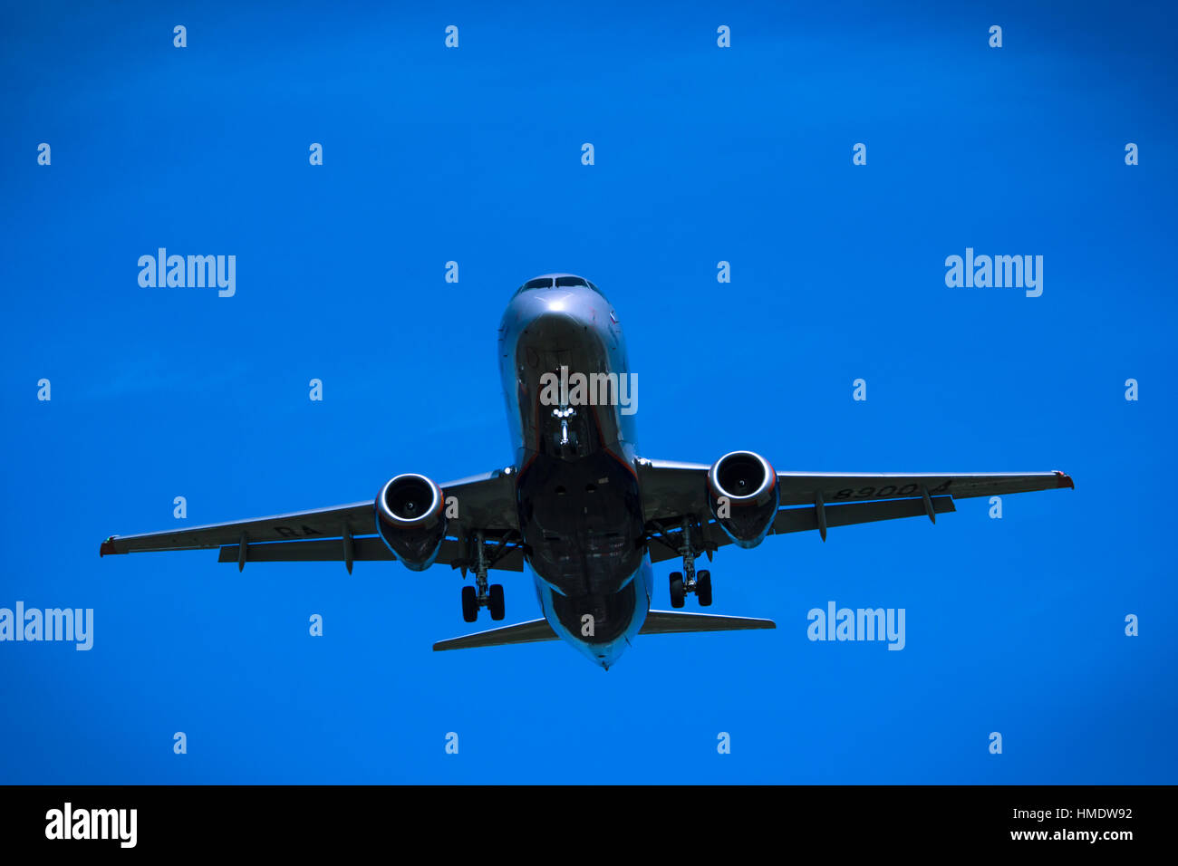 Jet airplane flying overhead close-up on a blue sky background Stock ...