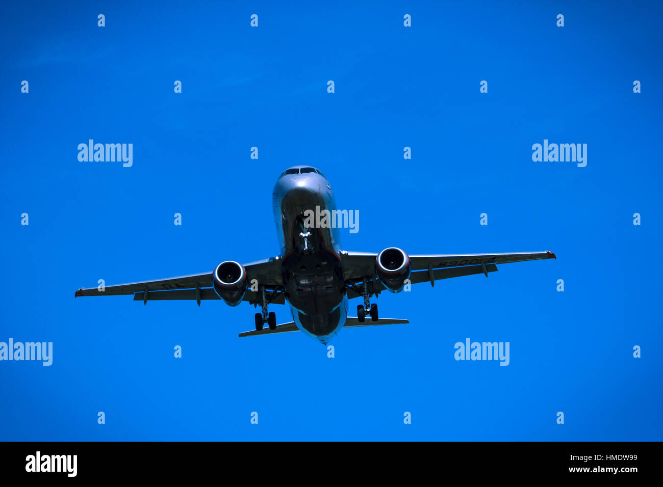 Jet airplane flying overhead close-up on a blue sky background Stock ...