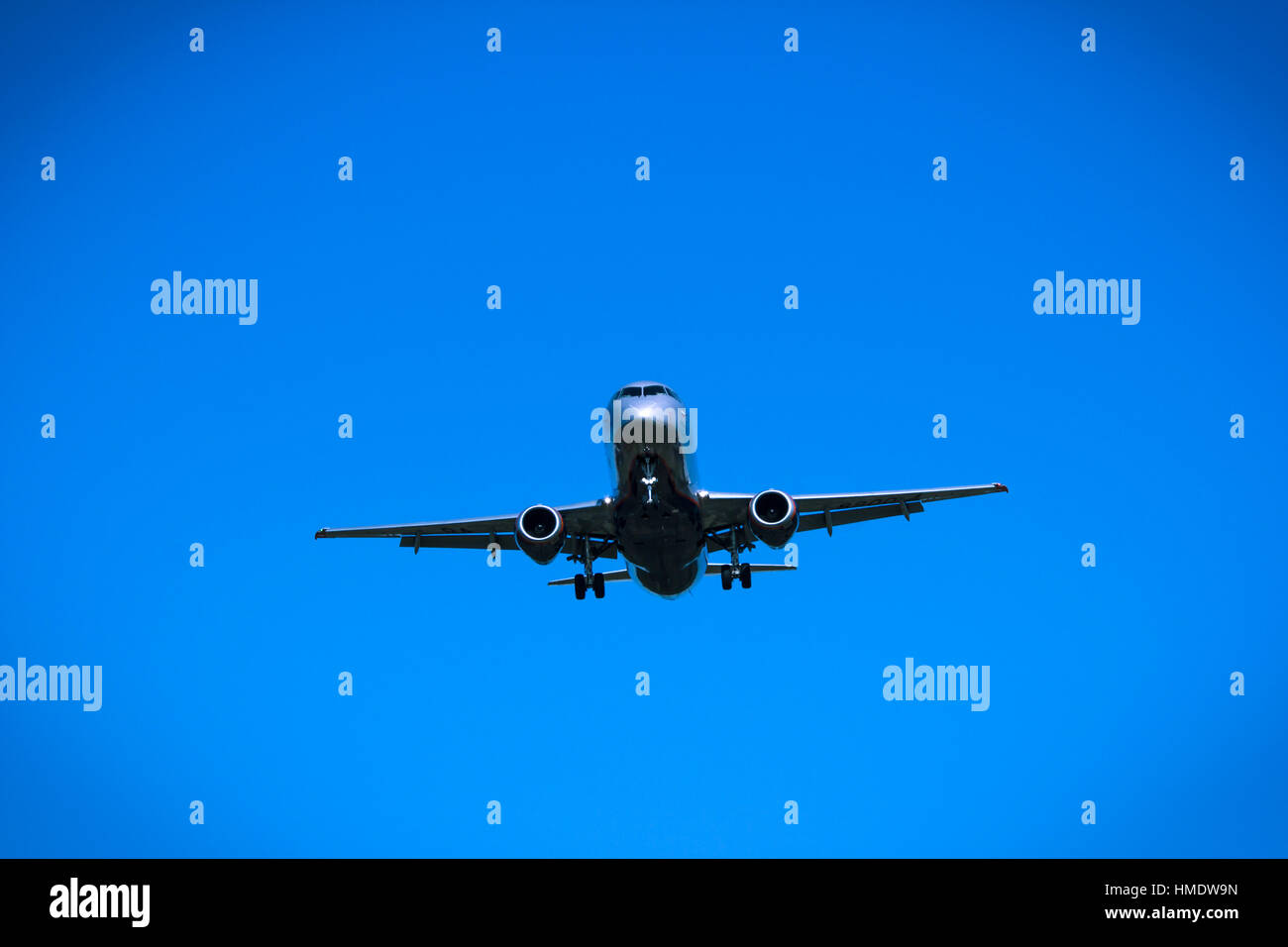 Jet airplane flying overhead close-up on a blue sky background Stock ...