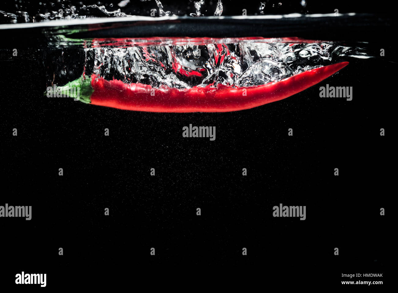 Chili in water splash isolated on the black background Stock Photo - Alamy