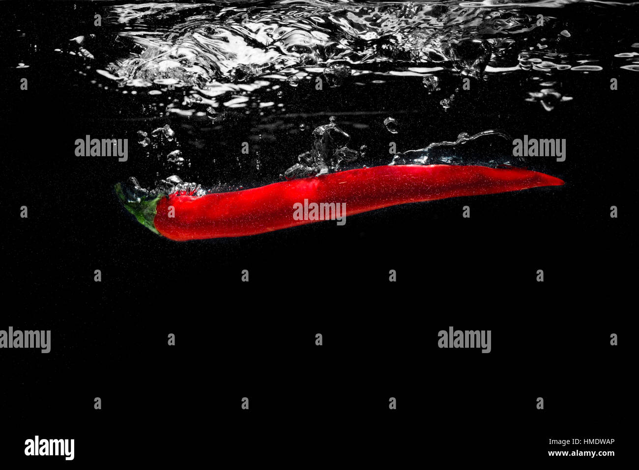 Chili in water splash isolated on the black background Stock Photo - Alamy