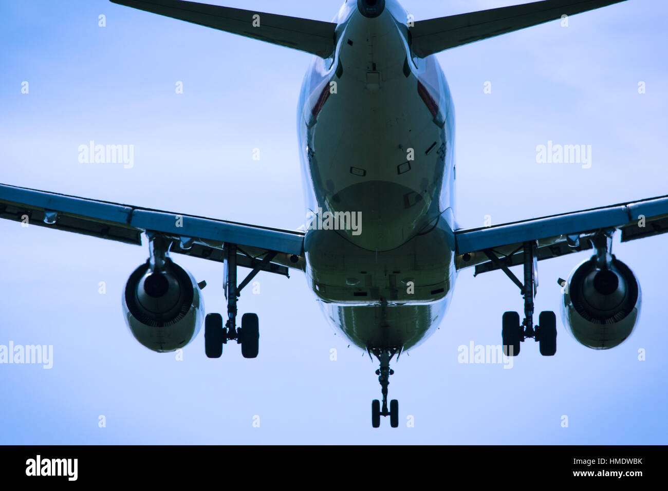Jet airplane flying overhead close-up on a blue sky background Stock ...