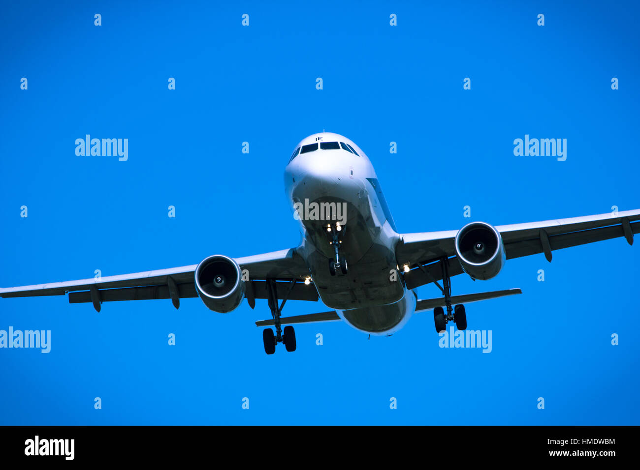 Jet airplane flying overhead close-up on a blue sky background Stock ...