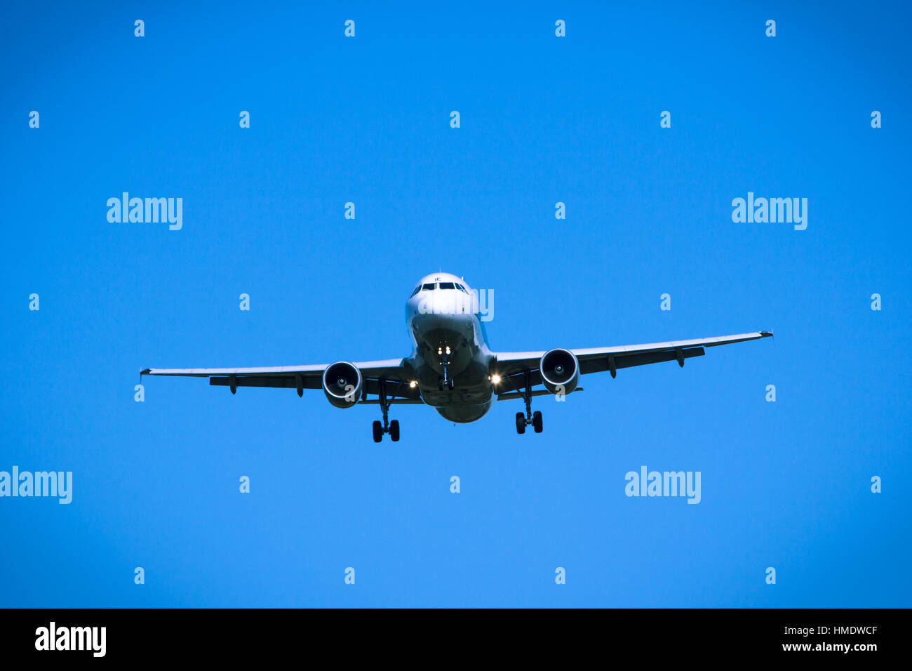 Jet airplane flying overhead close-up on a blue sky background Stock ...