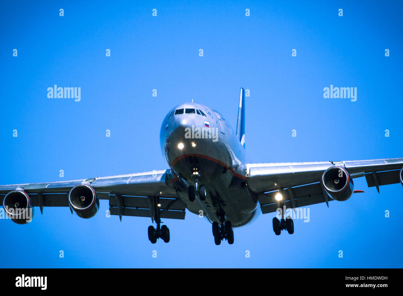 Jet airplane flying overhead close-up on a blue sky background Stock ...
