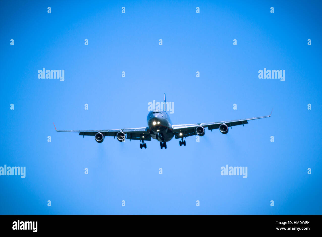 Jet airplane flying overhead close-up on a blue sky background Stock ...