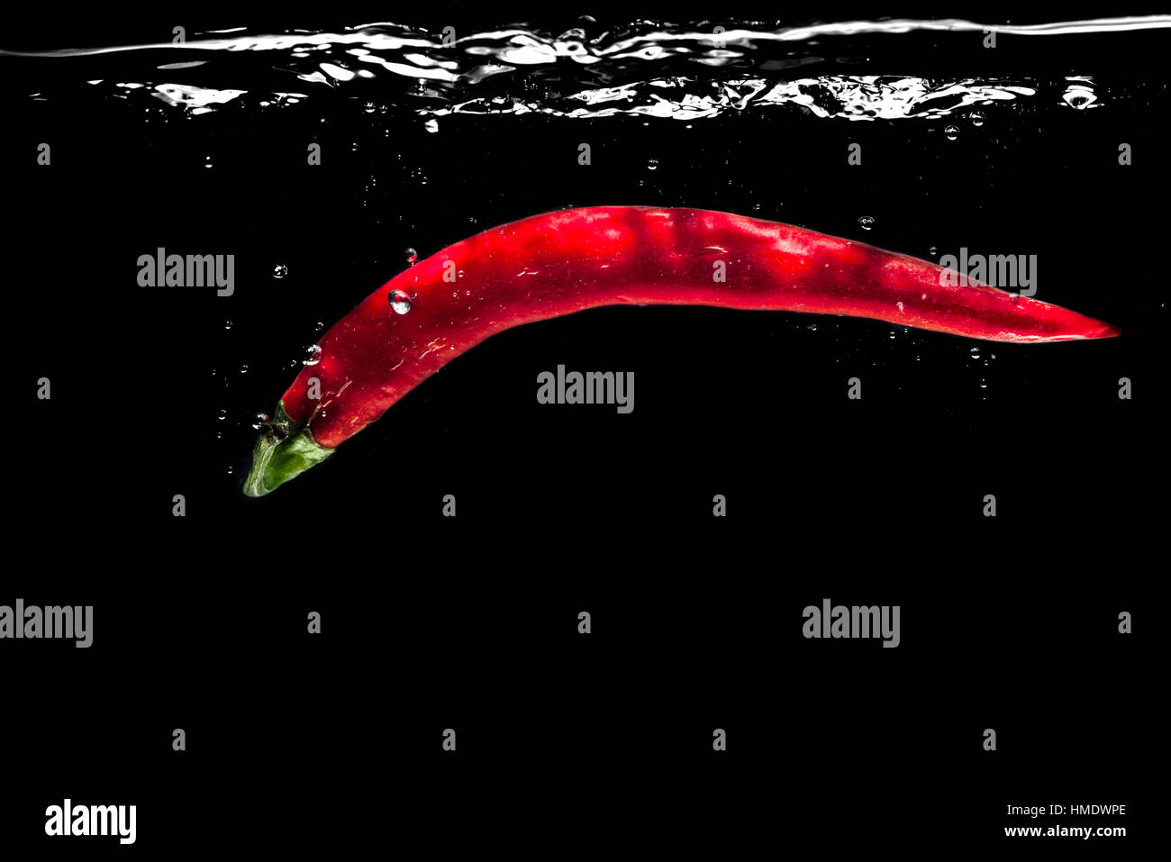 Chili in water splash isolated on the black background Stock Photo - Alamy