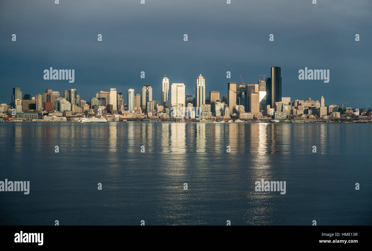 As the sun sets the buildings of the Seattle skyline are reflected in ...