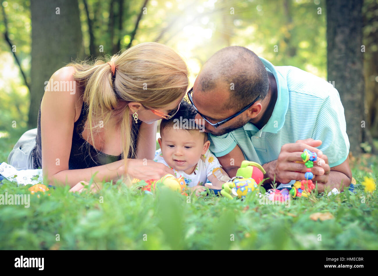 Happy interracial family is enjoying a day in the park. Little mulatto ...
