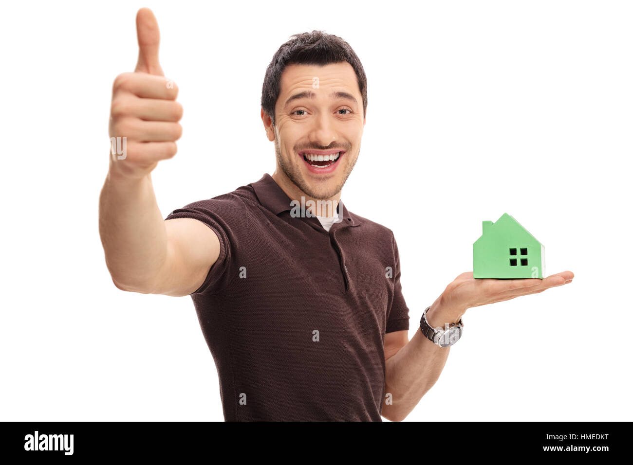 Delighted man making a thumb up gesture and holding a model house ...