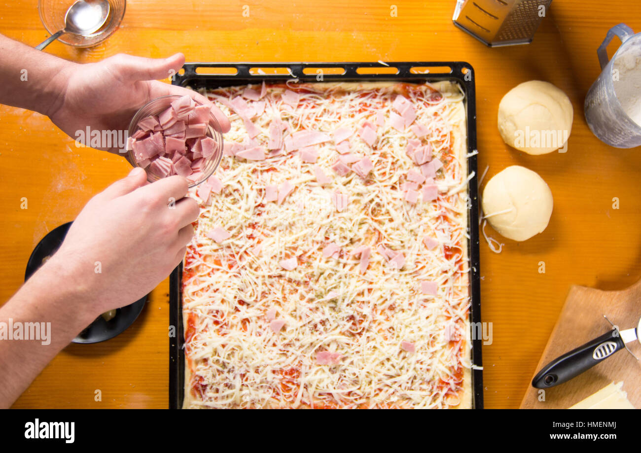 Male chef adding ingredients to pizza on a pan Stock Photo - Alamy
