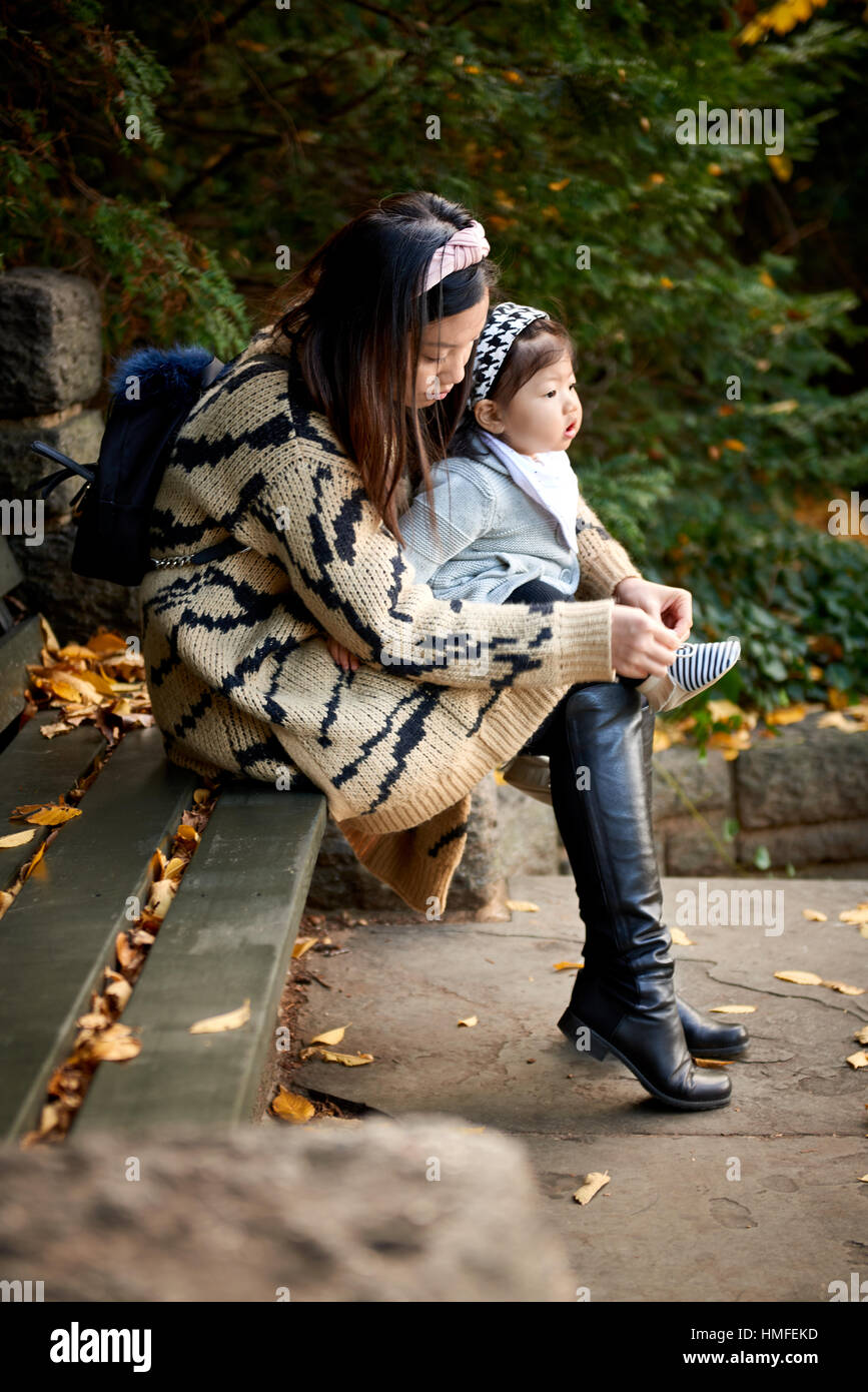 Mother and daughter sitting on bench in a park Stock Photo - Alamy