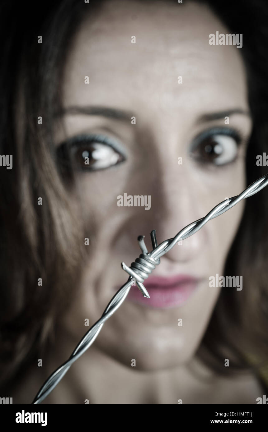 Scared woman behind barbed wire, a conceptual shot on gender violence ...