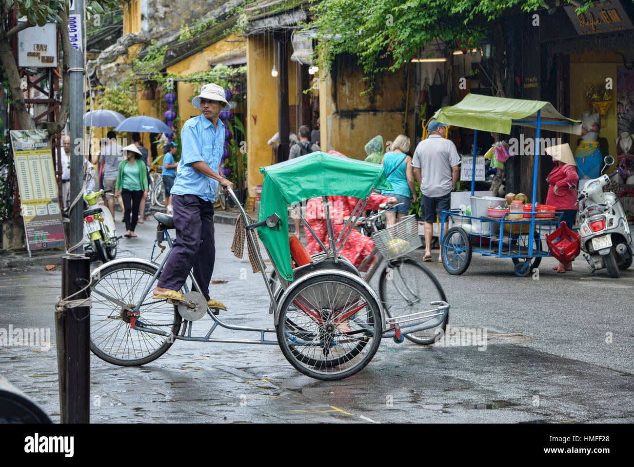 Cyclo driver in the rain, Hoi An, Vietnam Stock Photo - Alamy