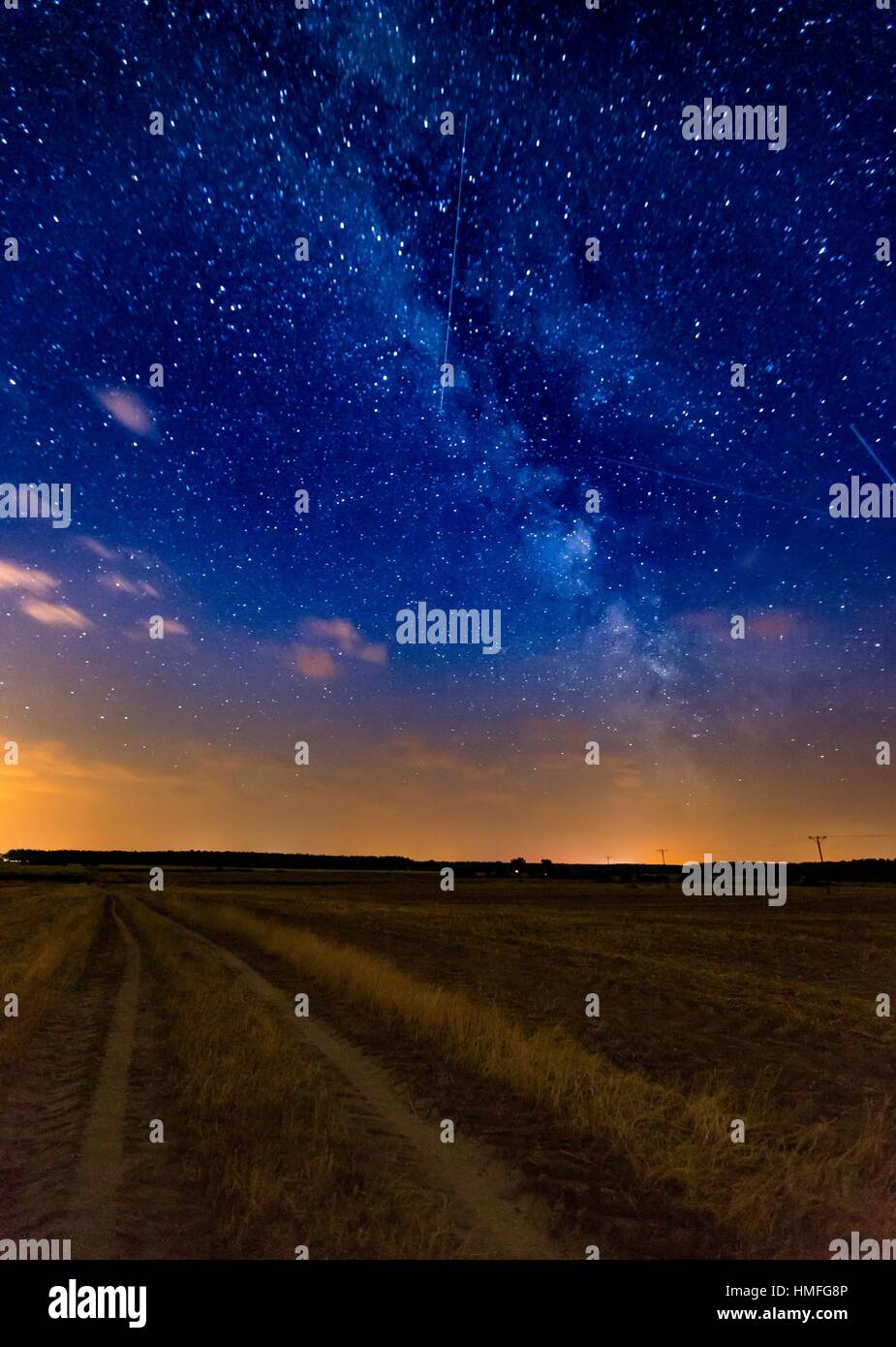 Milky way over stubble field and rural sandy road. Night landscape with ...