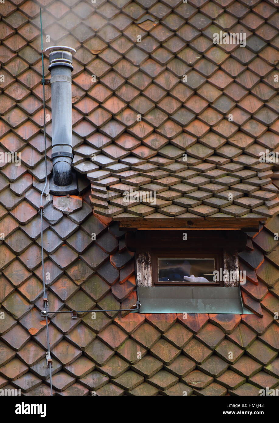 A smokey chimney and a small window in a tiled roof image with copy ...