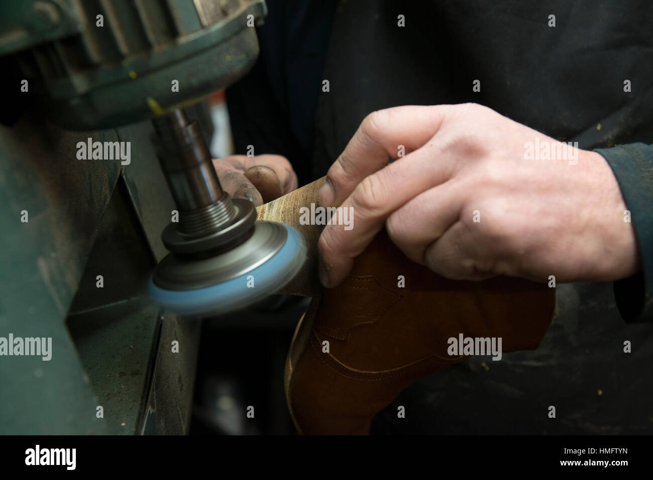 an old fashioned shoe repair / cobbler fixes shoes in his busy shop ...