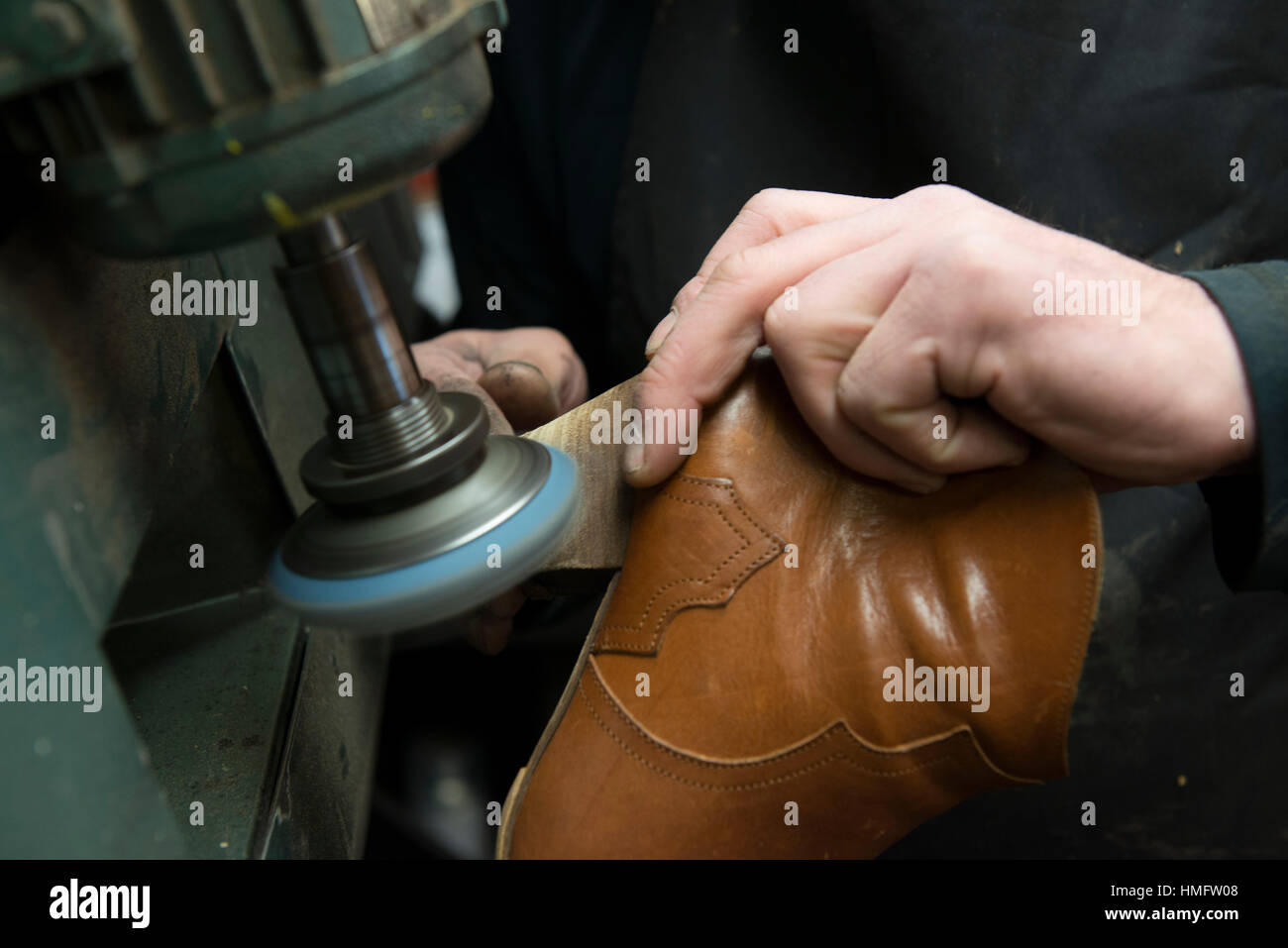 an old fashioned shoe repair / cobbler fixes shoes in his busy shop ...