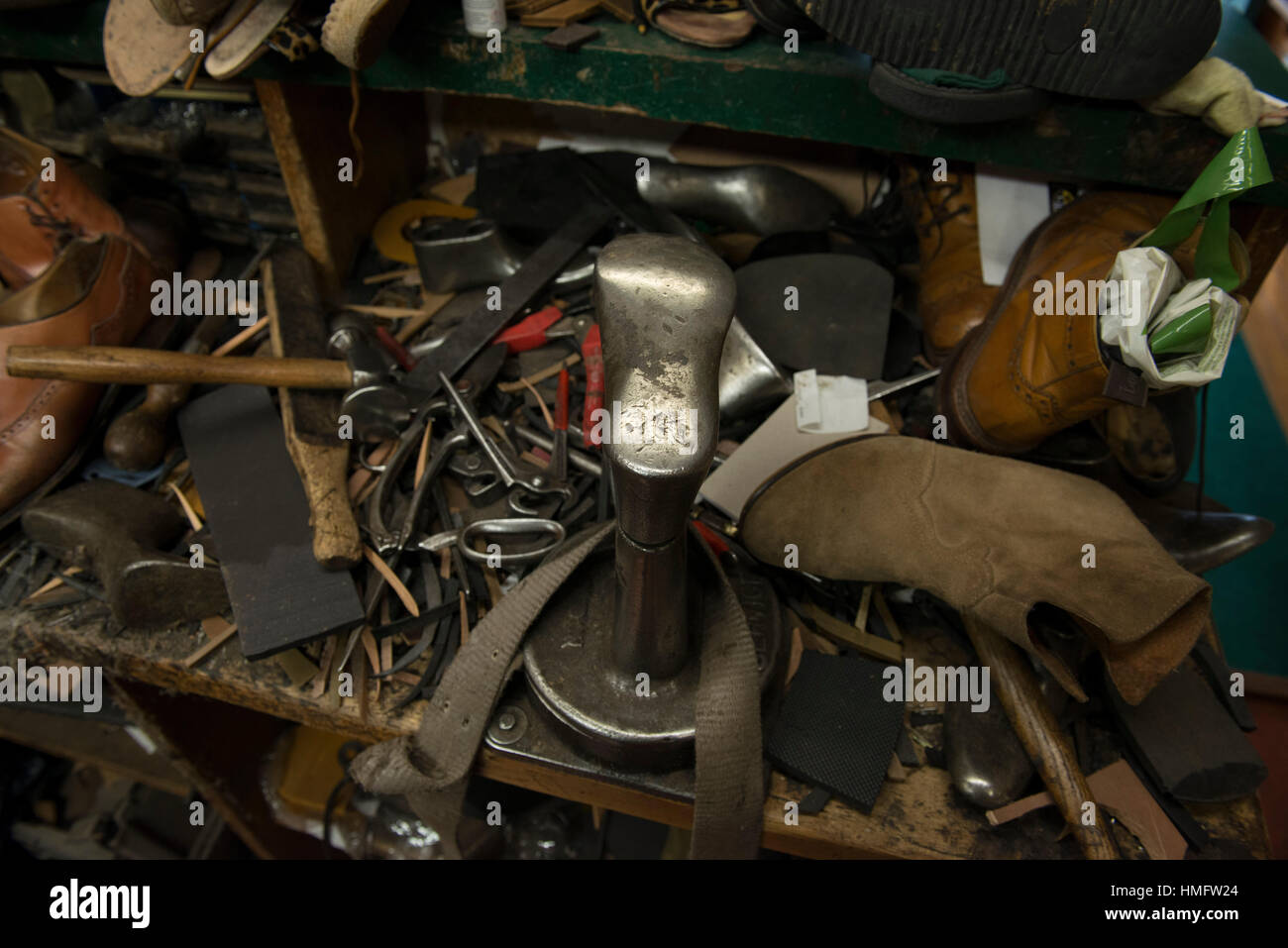 an old fashioned shoe repair / cobbler fixes shoes in his busy shop ...