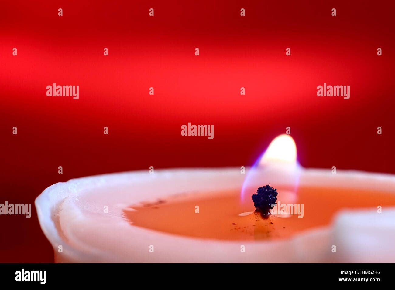 Flame of a burning wax candle isolated on a red background Stock Photo ...