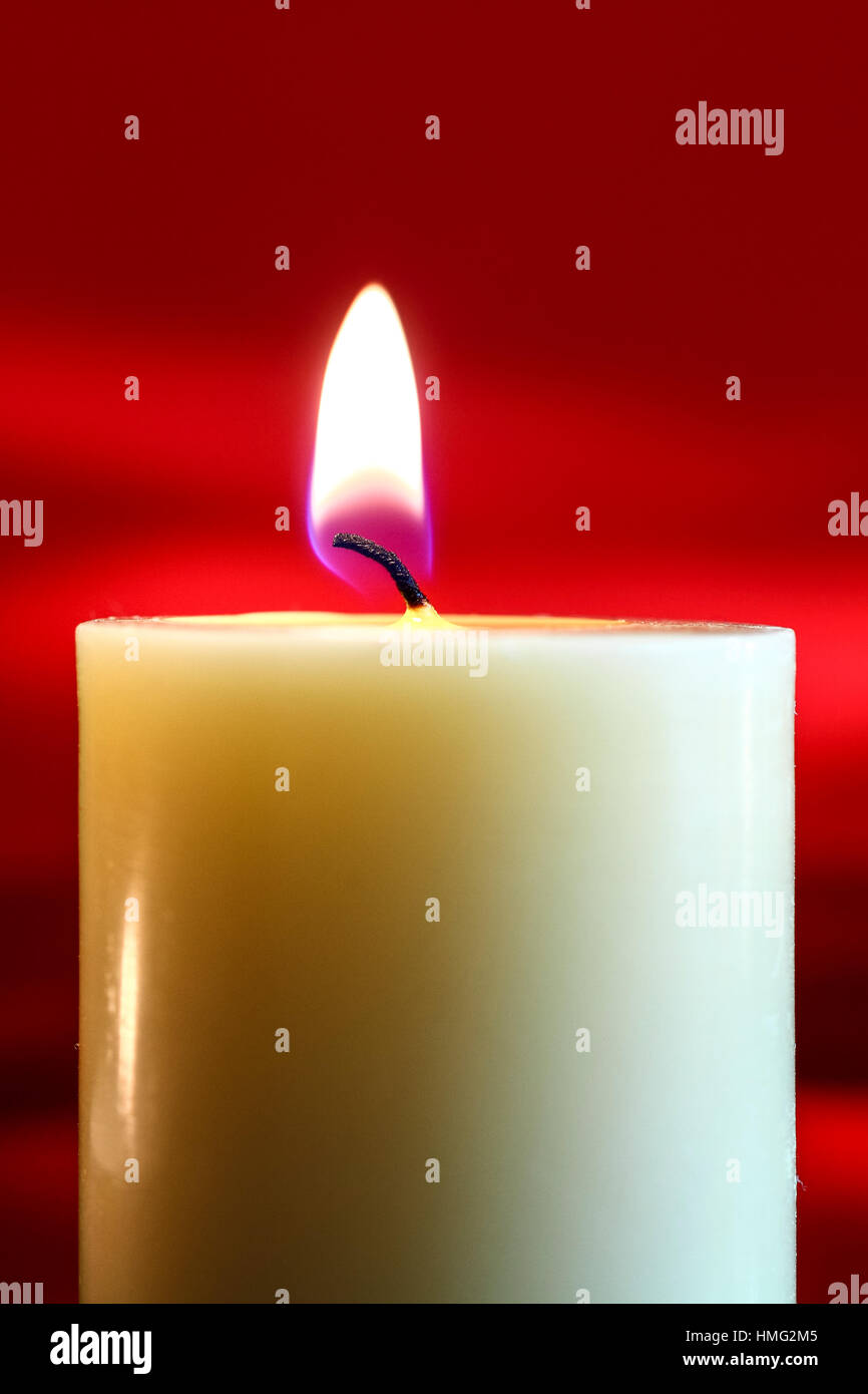 Flame of a burning wax candle isolated on a red background Stock Photo ...