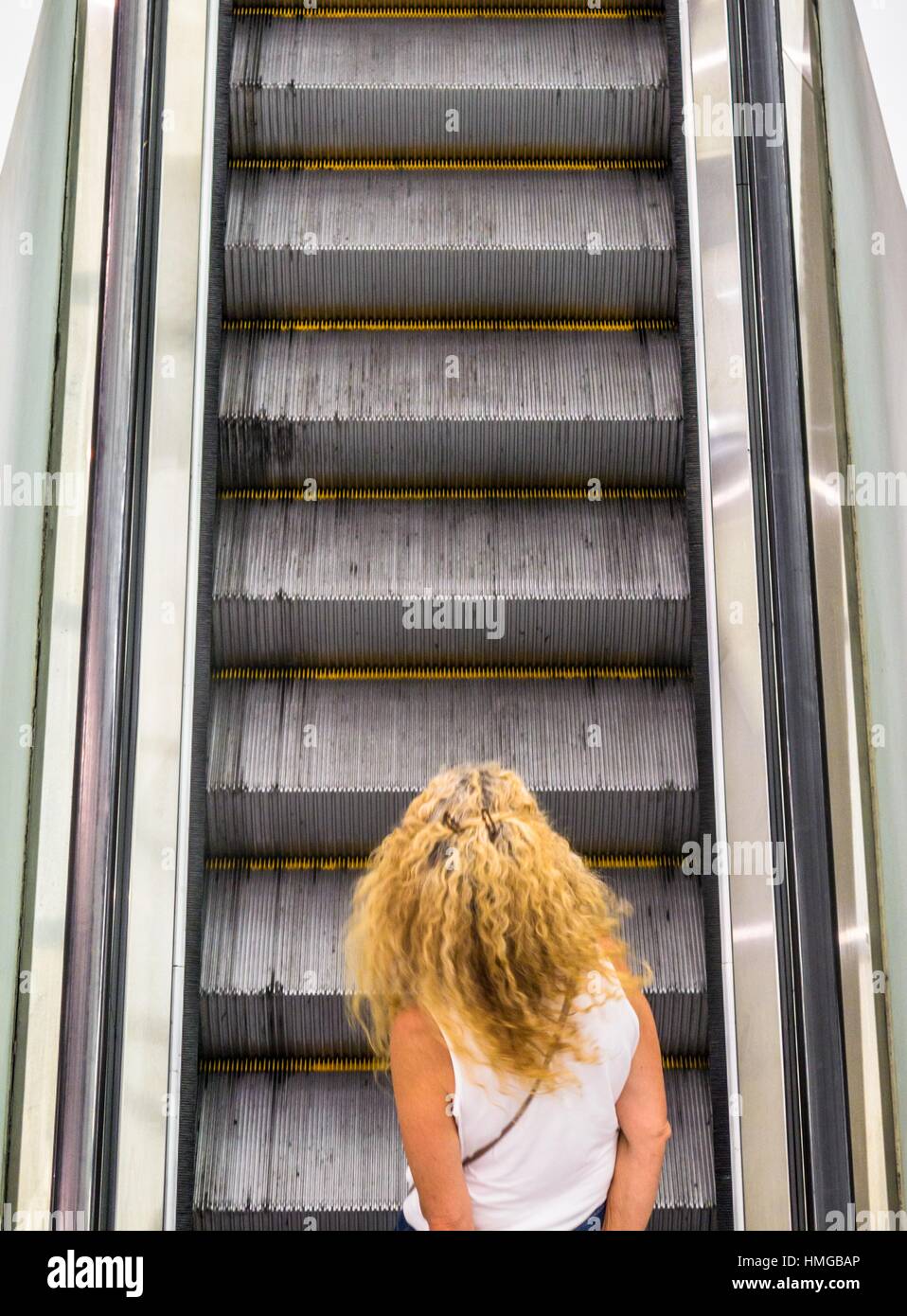 A woman going up to the next floor in a depar tment store - using an ...