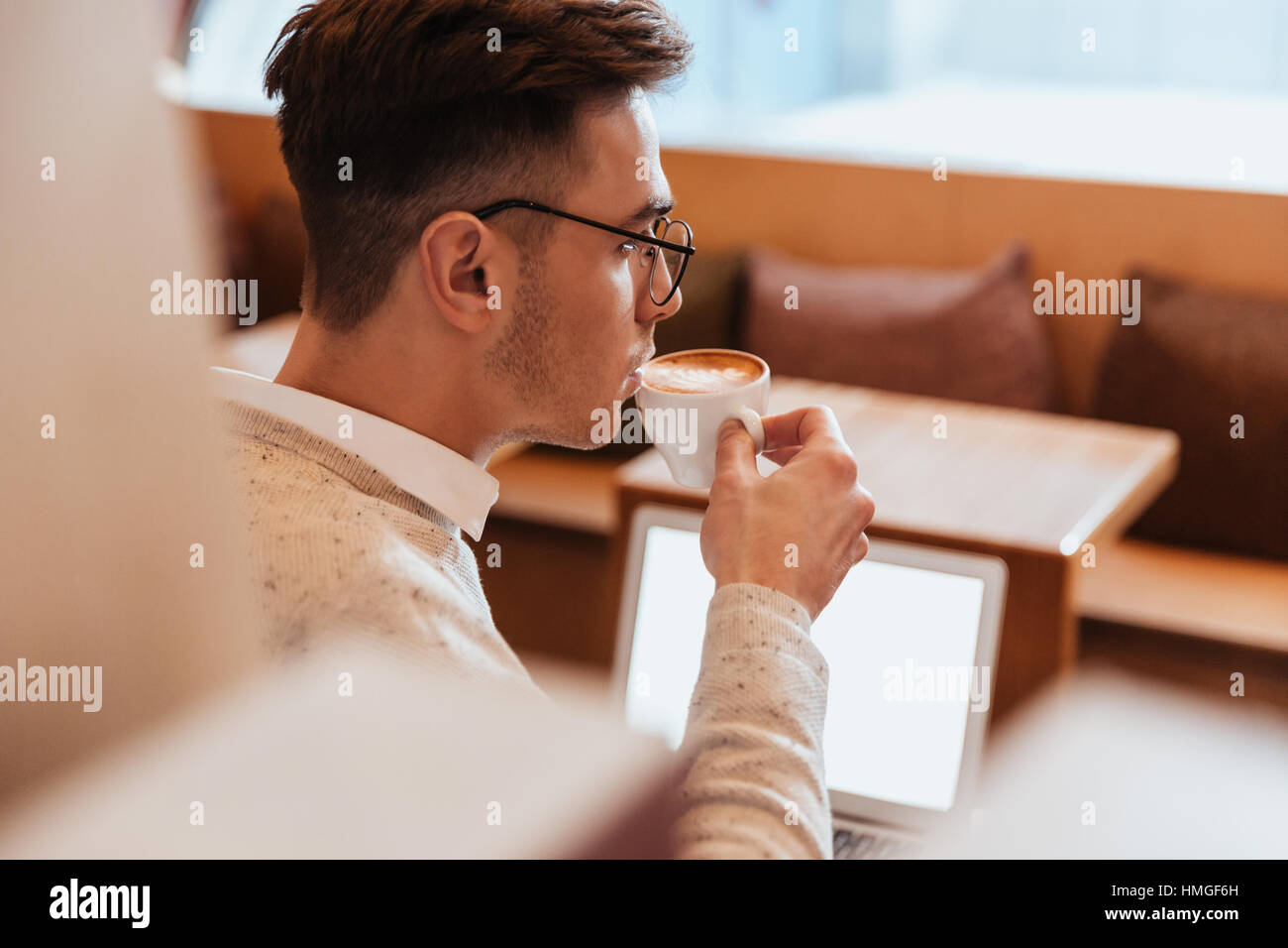 Back view photo of young attractive man sitting in cafe while using ...