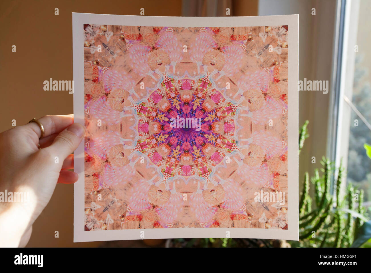 Hand holding abstract mandala picture inside home interior Stock Photo ...