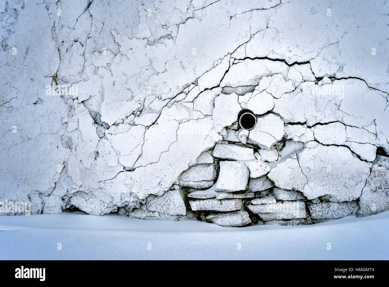 Single water pipe protruding from a cracked white plaster wall with ...