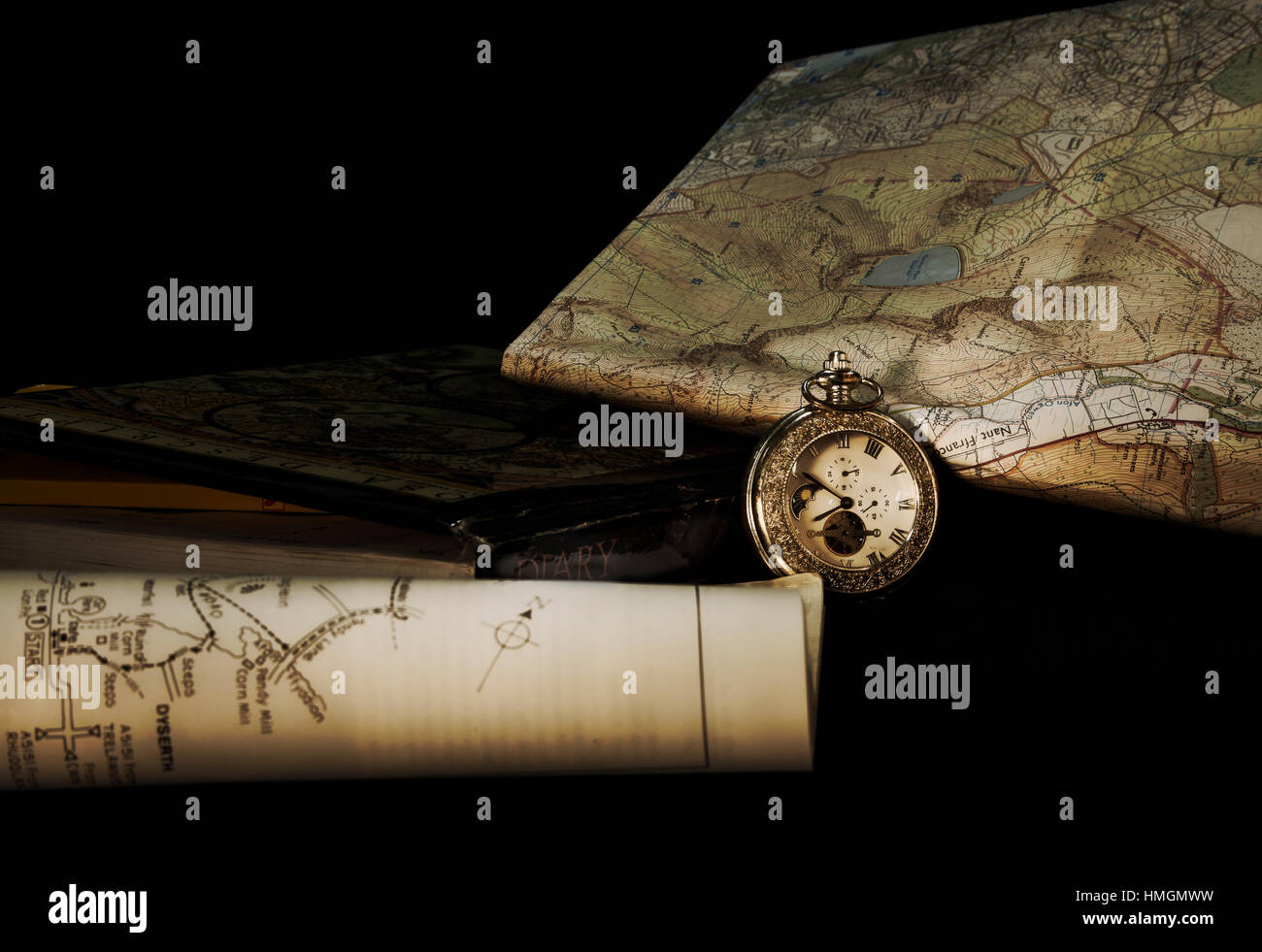 A collection of maps to use for navigation and hiking, a watch and a ...