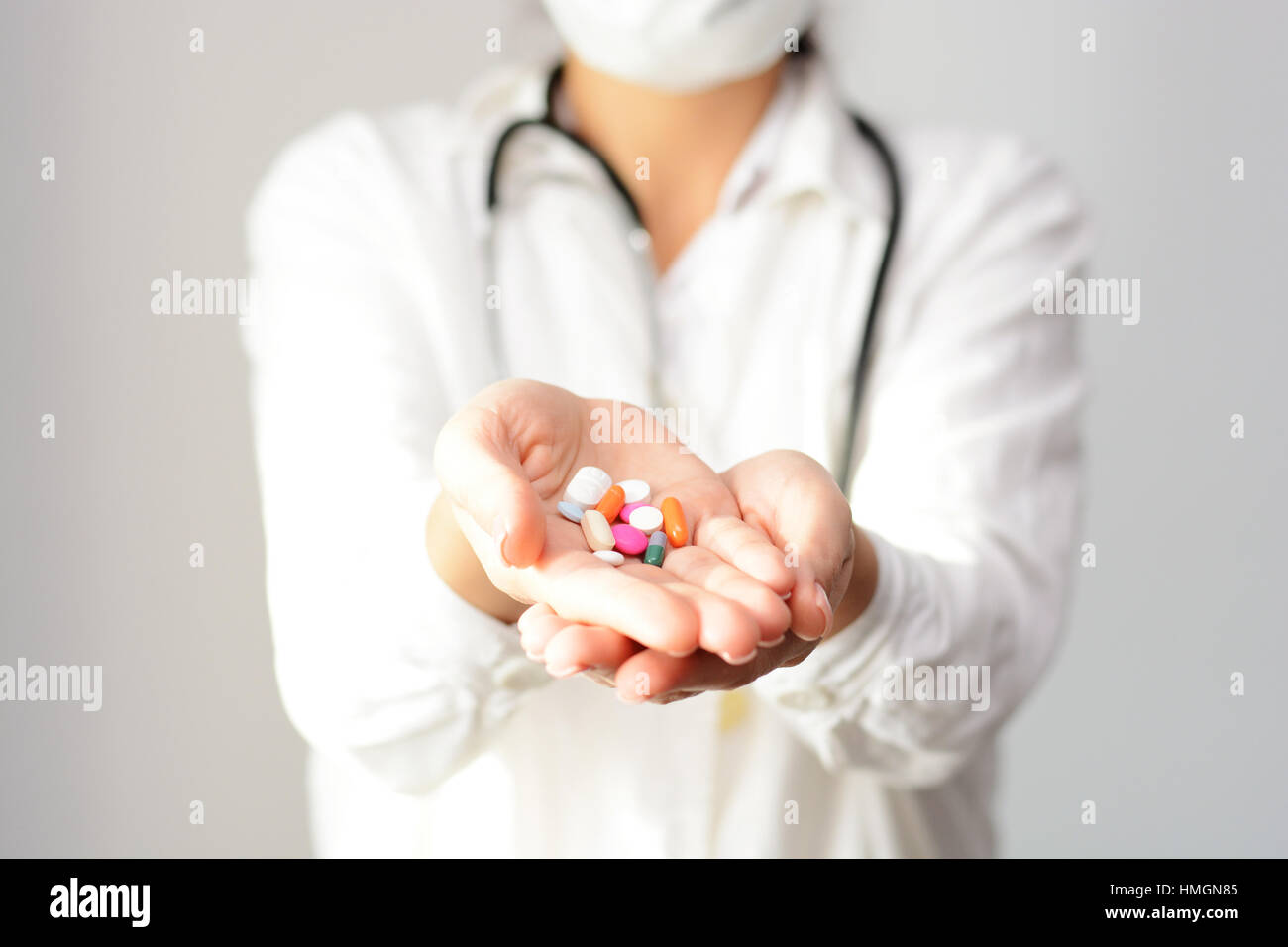 Female doctor displaying a handful of tablets and pills in her palm ...