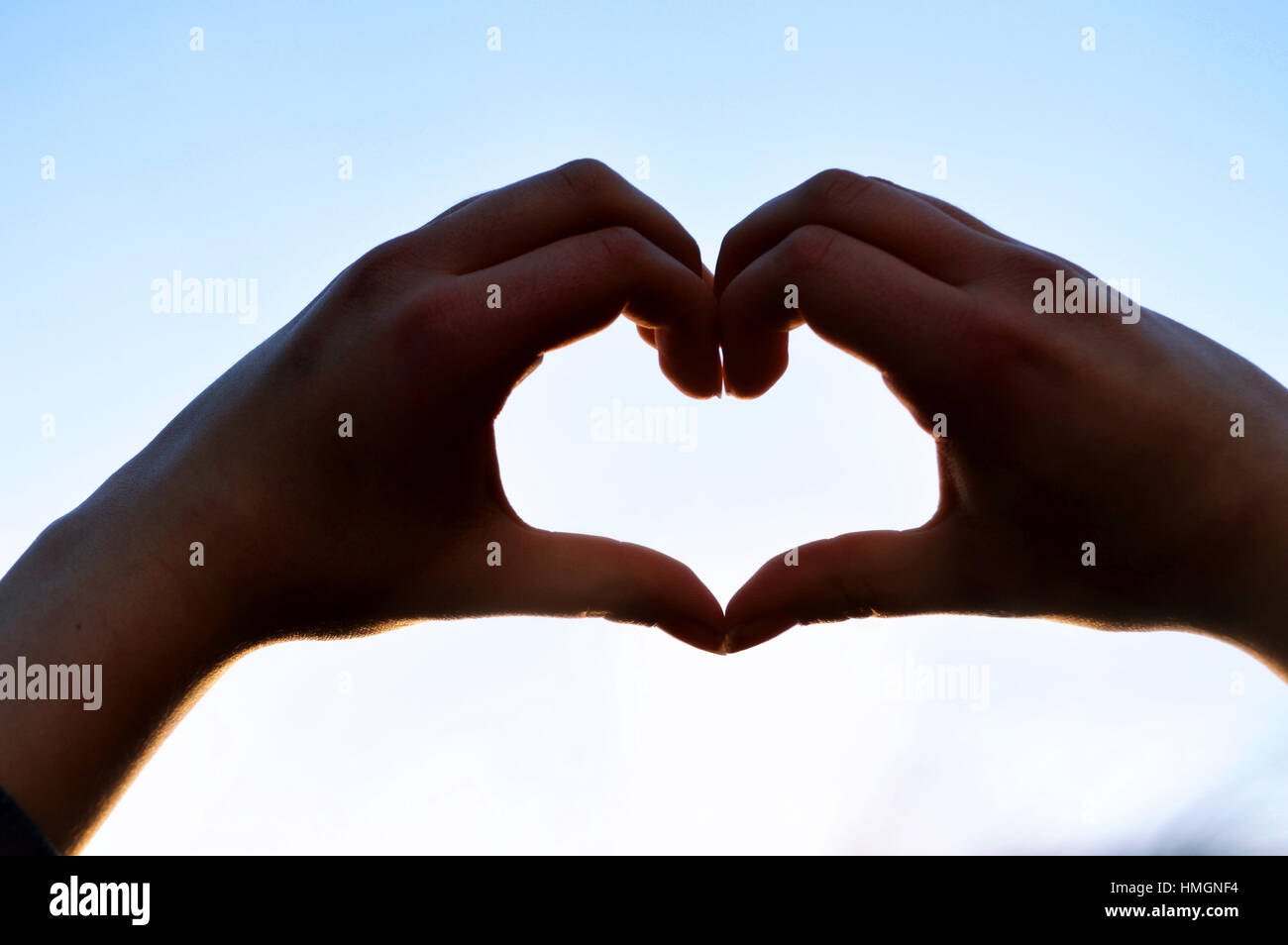 Two hands creating a heart shape against blue sky Stock Photo - Alamy
