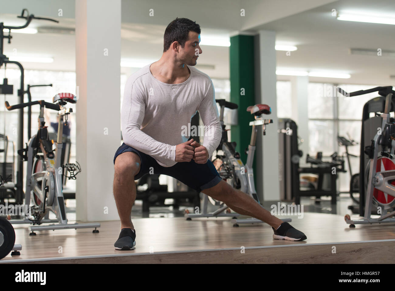 Muscular Man Stretches At The Floor In A Gym And Flexing Muscles ...