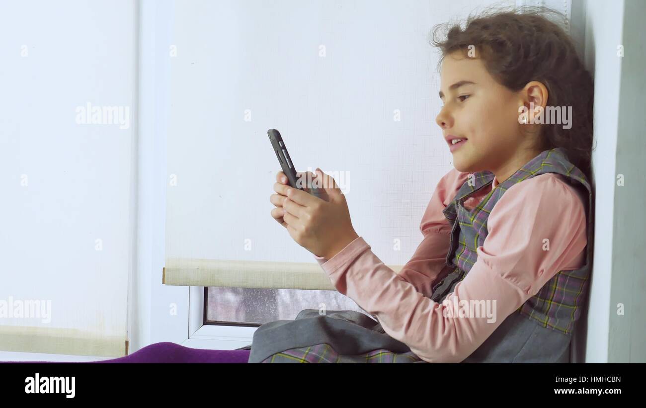 teen girl sitting on web a window sill plays the online game for ...