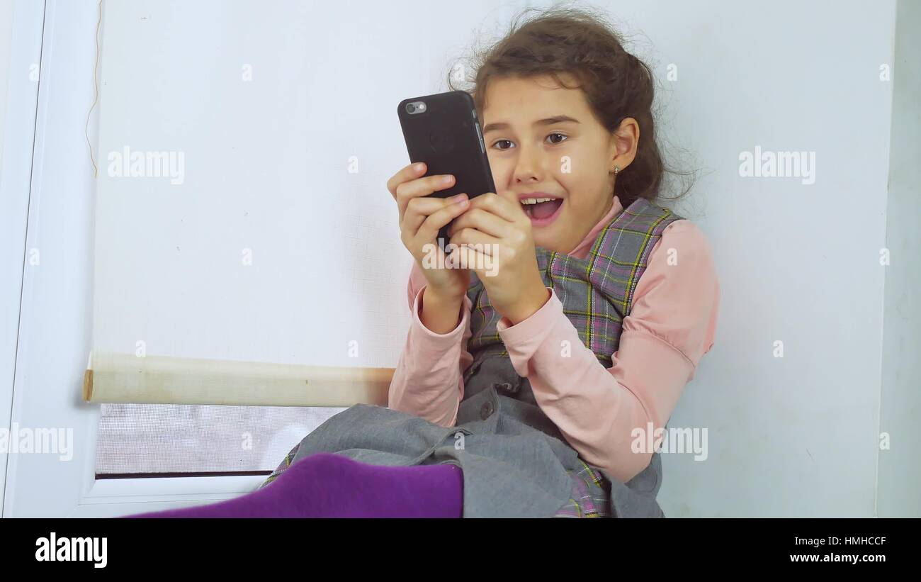 teen girl sitting on a window sill web plays the online game for ...