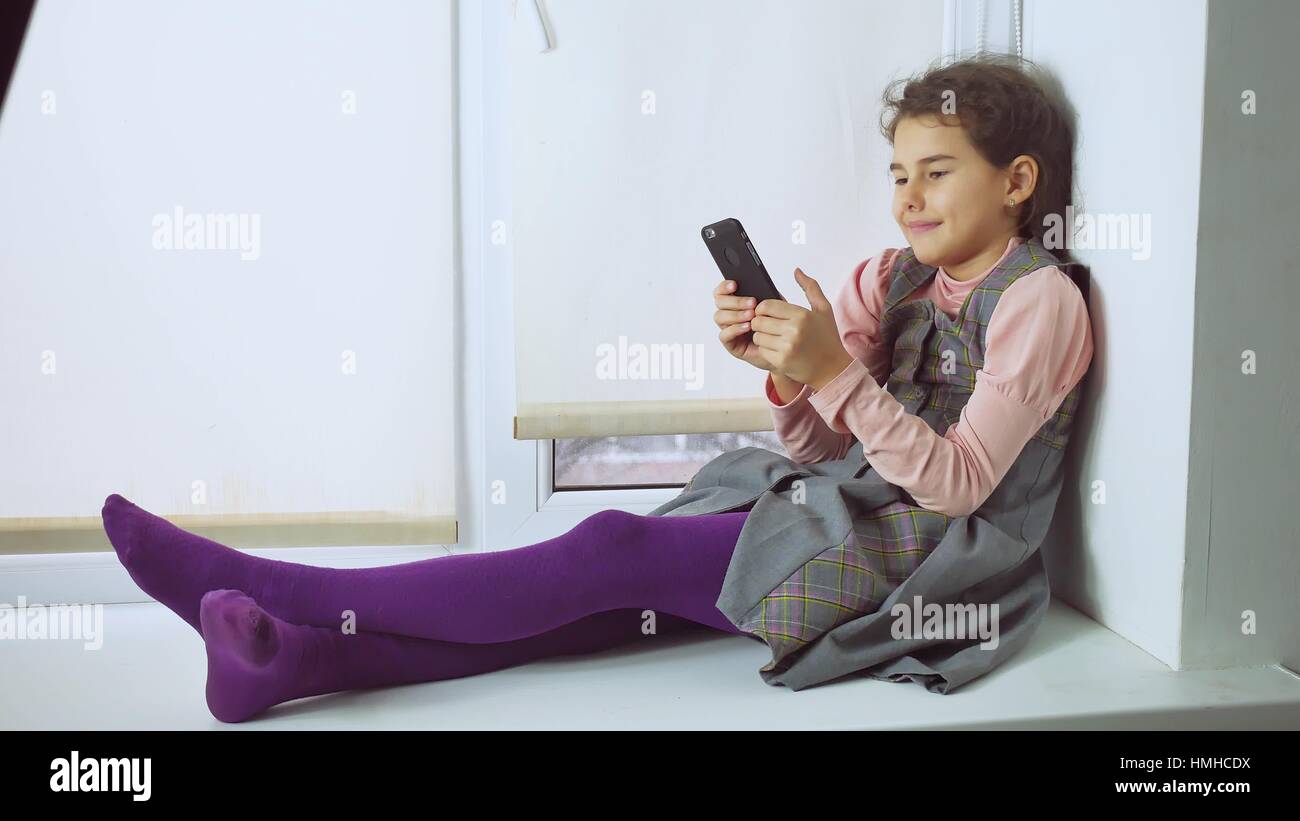 teen girl sitting on a window sill plays the online game web for ...