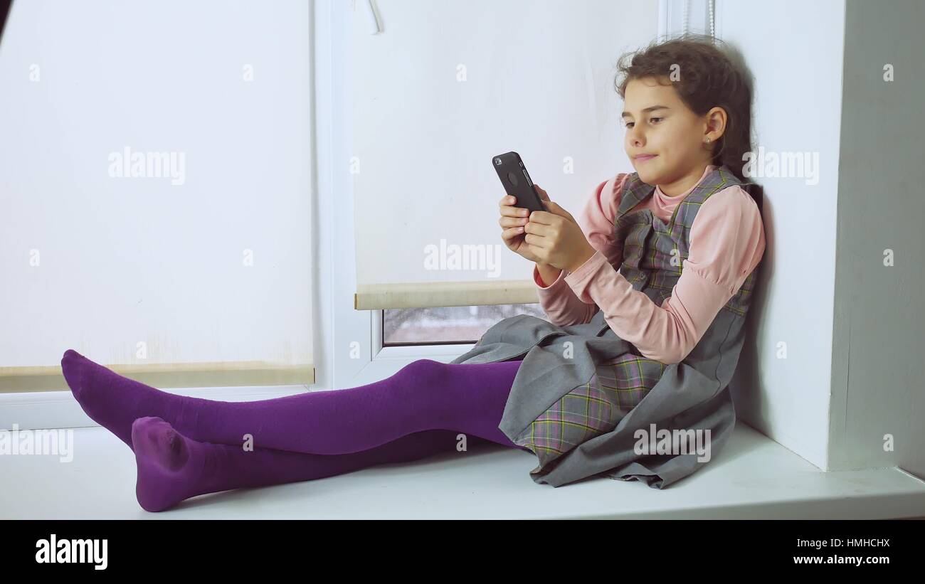 teen girl sitting on a window sill plays the online game web for ...