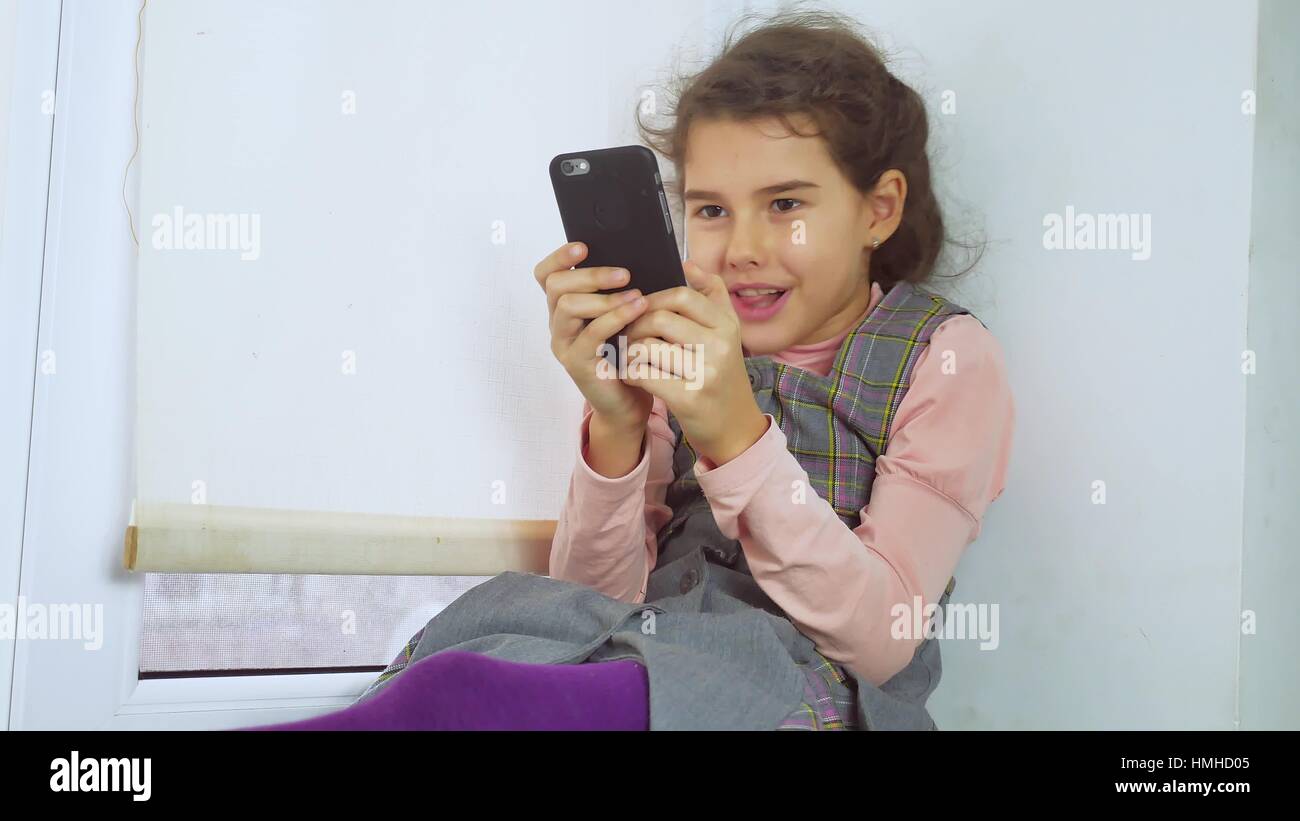 teen girl sitting on a window sill web plays the online game for ...