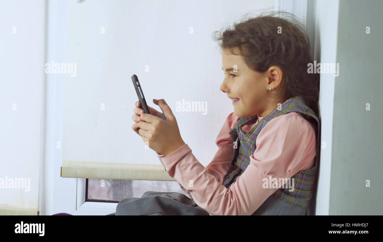 teen girl sitting on web a window sill plays the online game for ...