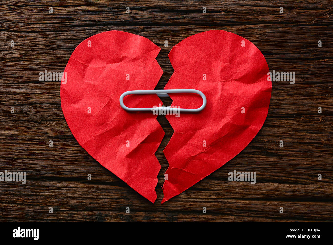 Paper broken heart with paperclips on wooden background Stock Photo - Alamy