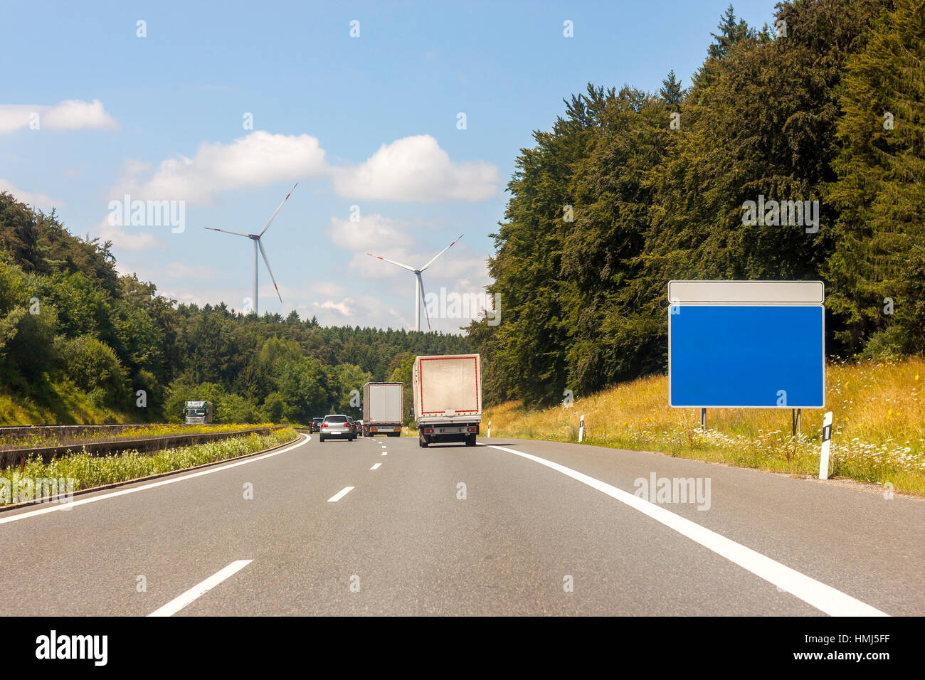 Empty blue sign board at the roadside on freeway in summer landscape ...