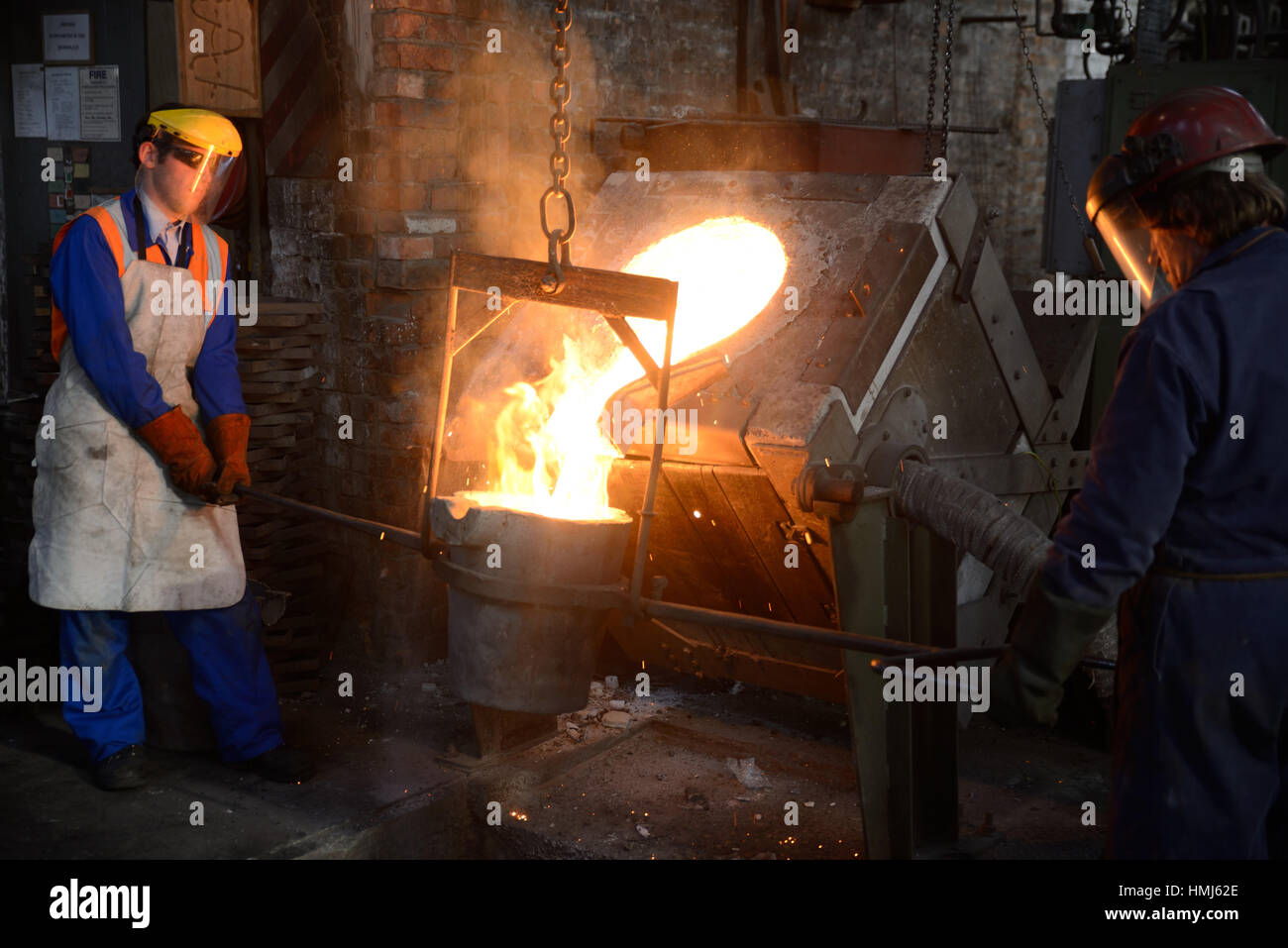 Foundrymen pour molten iron from an induction furnace into the ladel at ...
